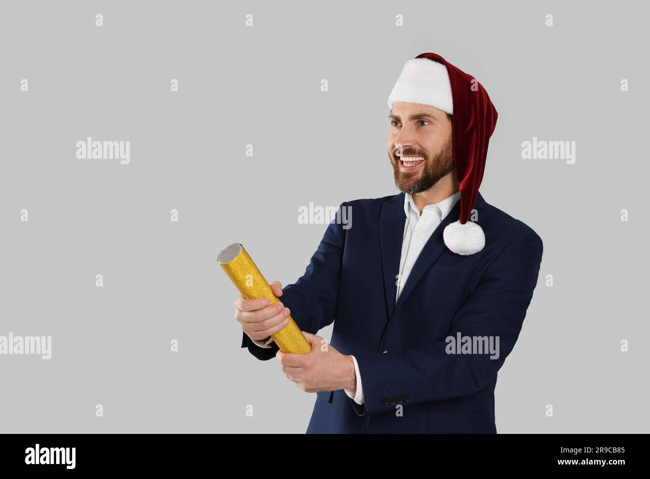 Happy man with party popper on light grey background. Space for text ...
