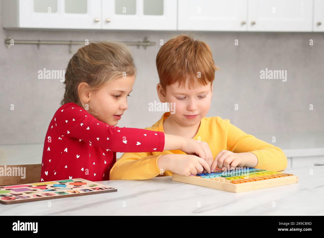 Children playing with math game kit at white marble table in kitchen ...