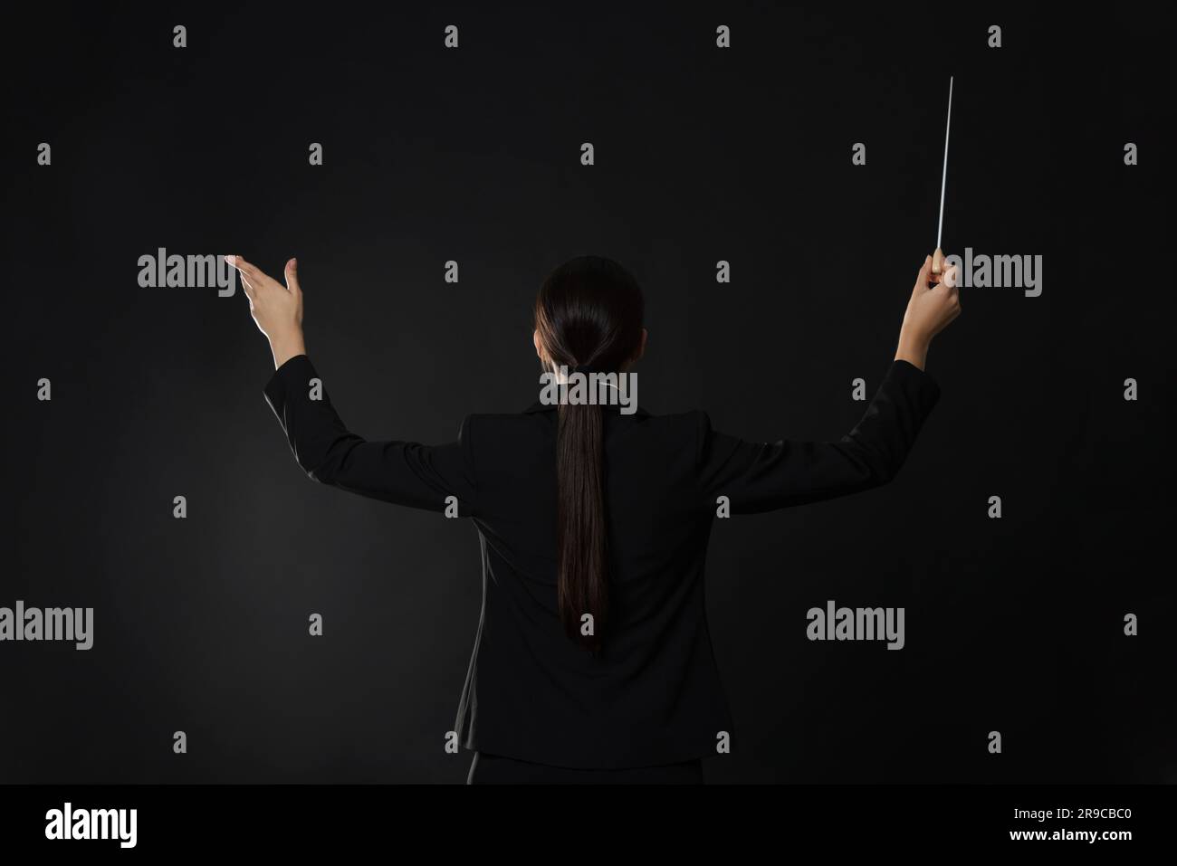 Professional conductor with baton on dark background, back view Stock ...