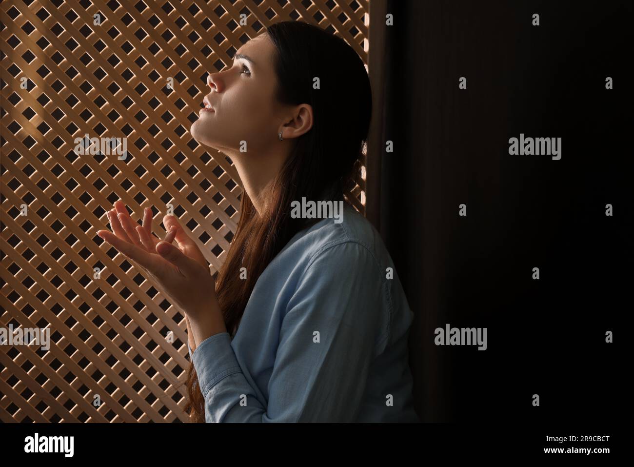 Woman praying to God during confession in booth Stock Photo - Alamy