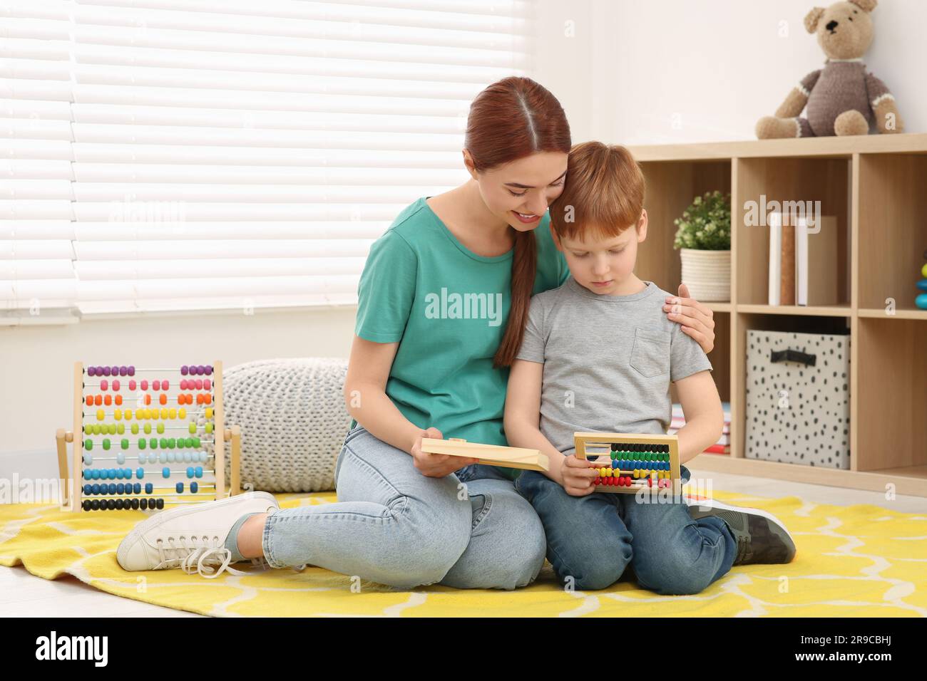 Happy mother and son playing with different math game kits on floor in ...