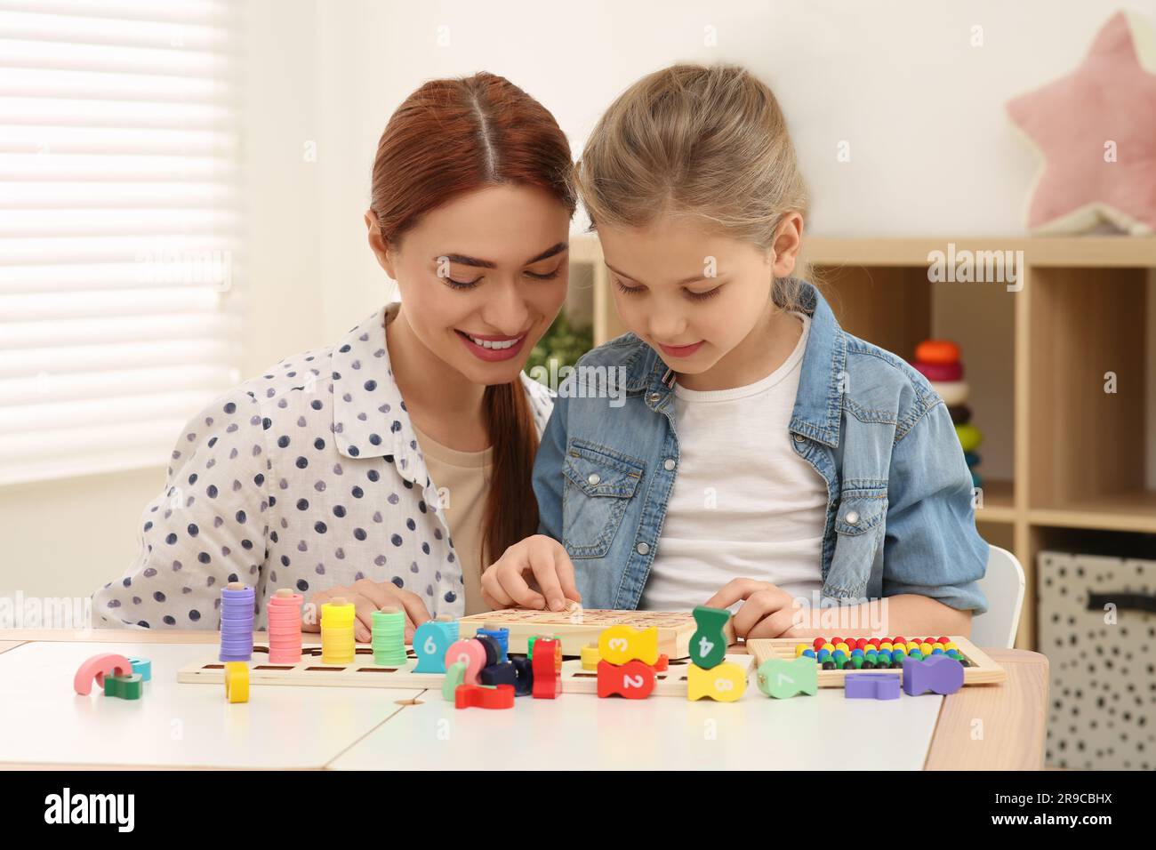 Happy mother and daughter playing with different math game kits at desk ...