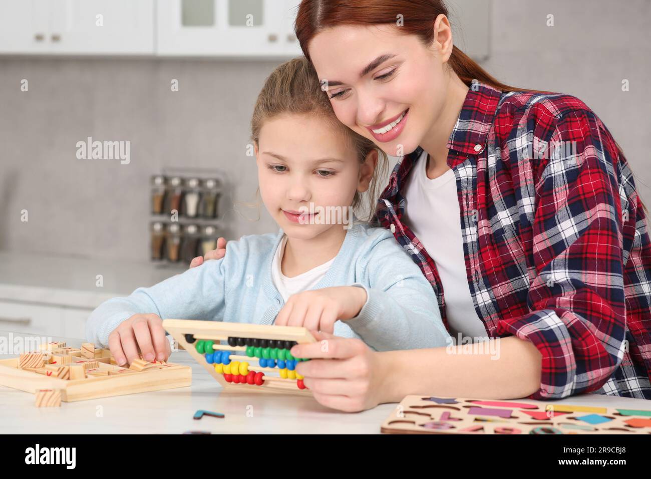 Happy mother and daughter playing with different math game kits at ...