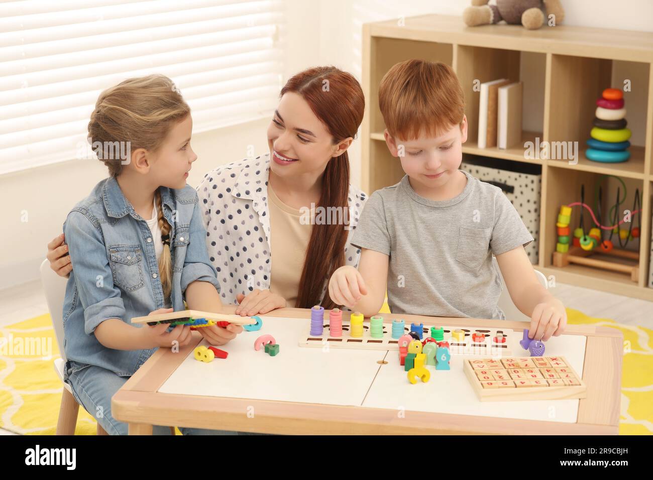 Happy mother and children playing with different math game kits at desk ...