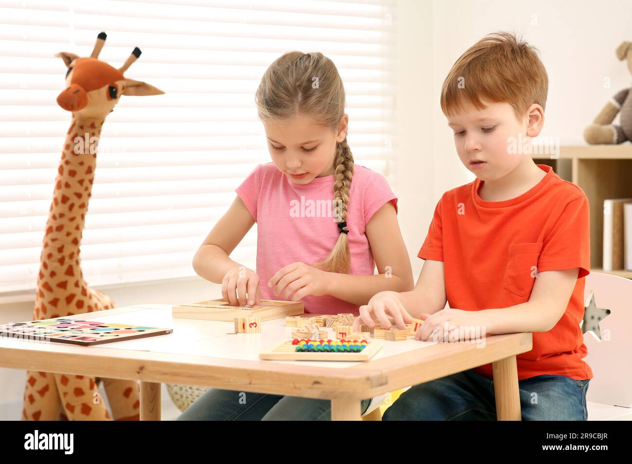 Children playing with different math game kits at desk in room. Study ...