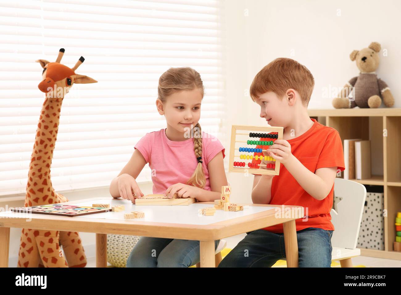 Children playing with different math game kits at desk in room. Study ...