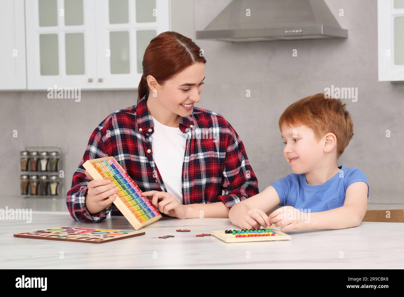 Happy mother and son playing with different colorful cubes and ...