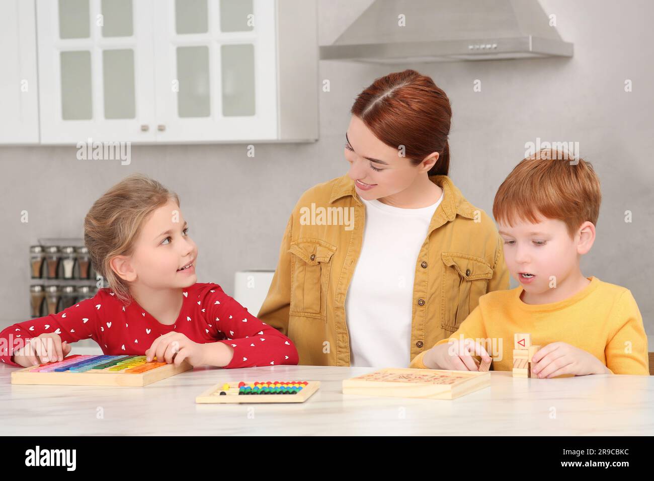 Happy mother and children playing with different math game kits at ...