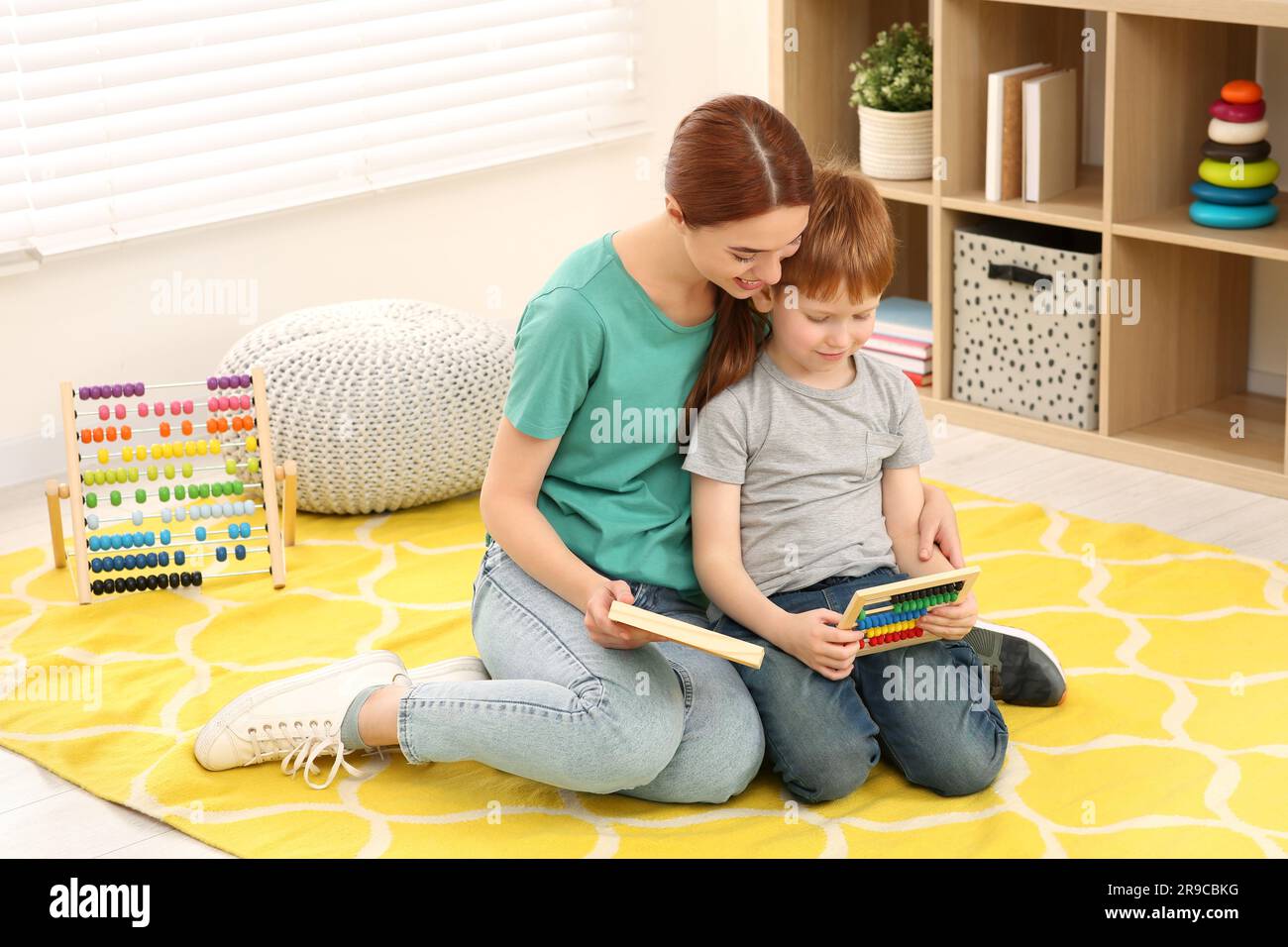 Happy mother and son playing with different math game kits on floor in ...