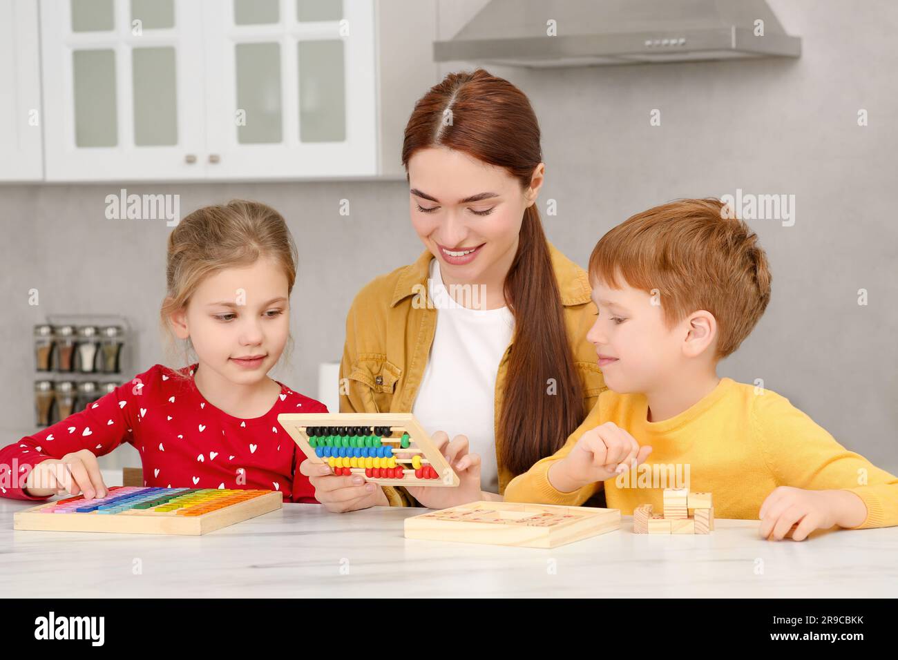 Happy mother and children playing with different math game kits at ...