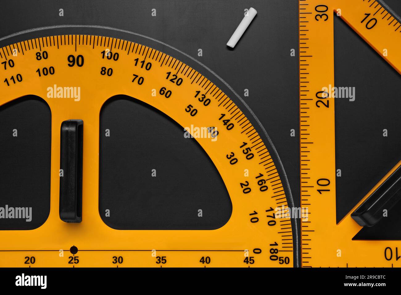 Protractor, triangle ruler and chalk on black table, flat lay Stock ...