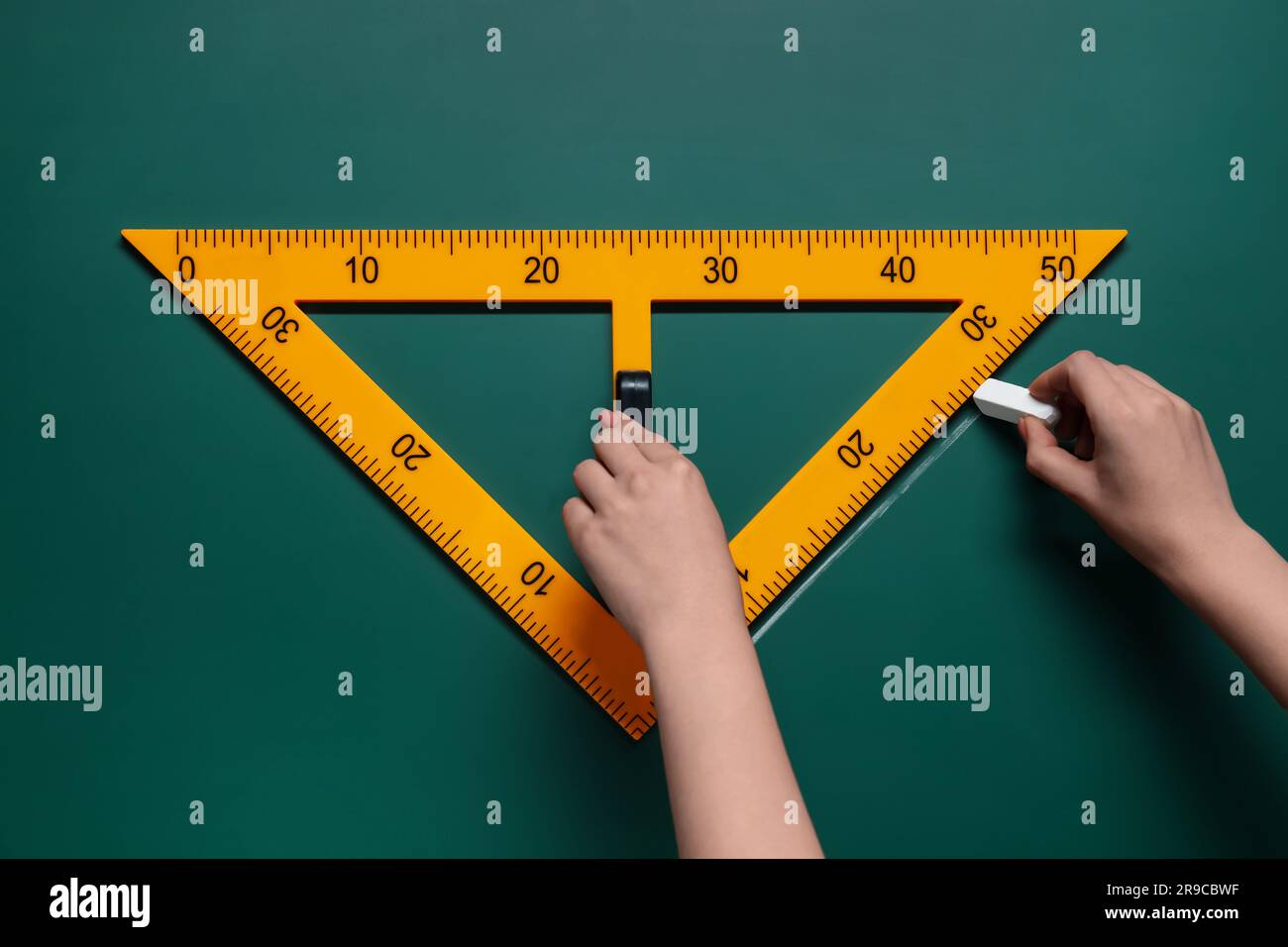 Woman drawing with chalk and triangle ruler on green board, closeup ...
