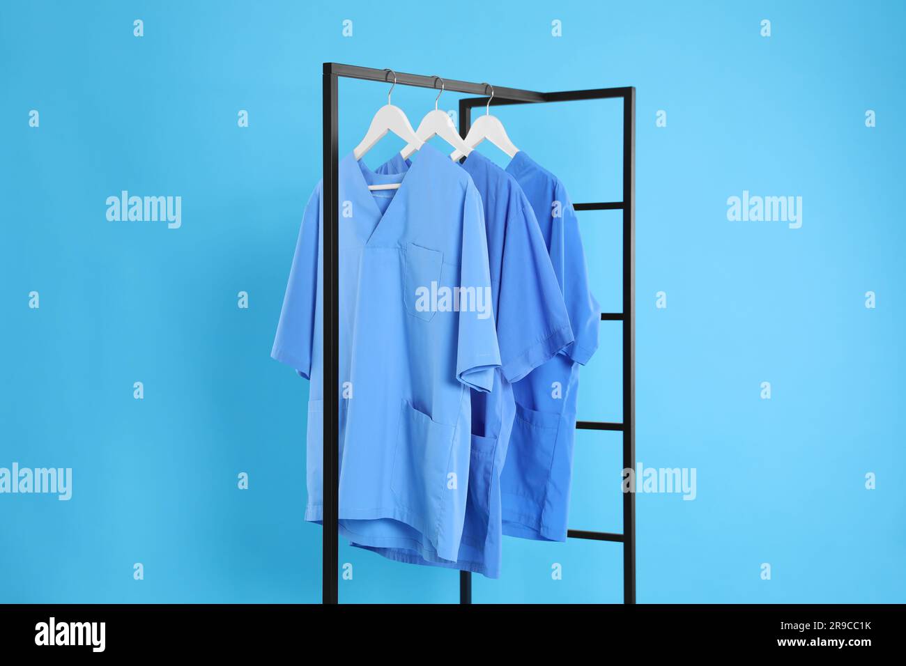 Medical uniforms on metal rack against light blue background Stock ...