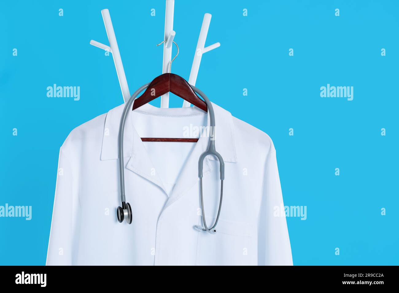 White medical uniform and stethoscope hanging on rack against light ...