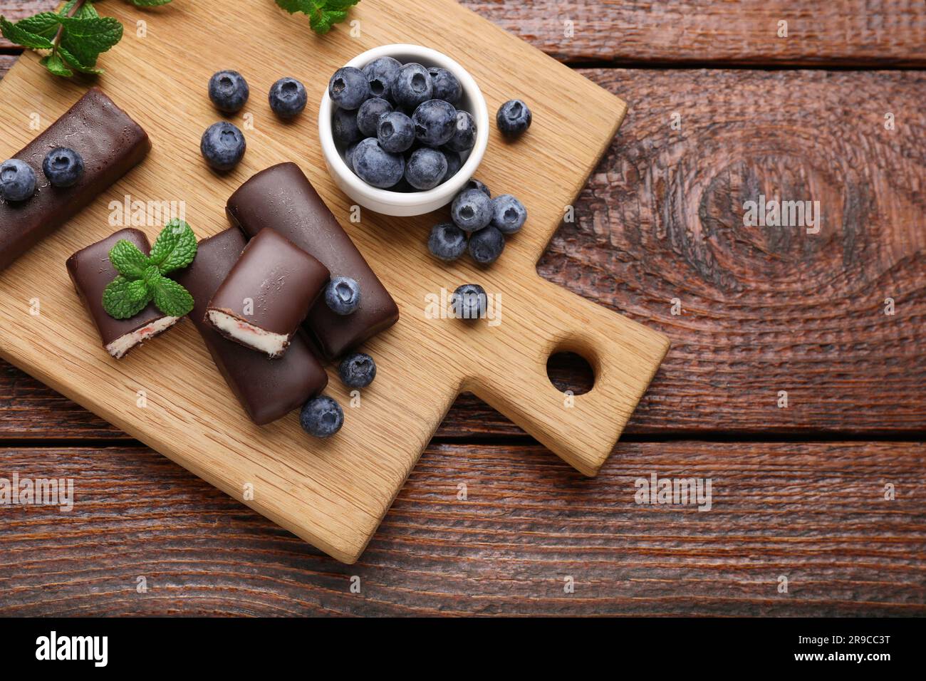 Delicious glazed curd snacks with fresh blueberries and mint on wooden ...