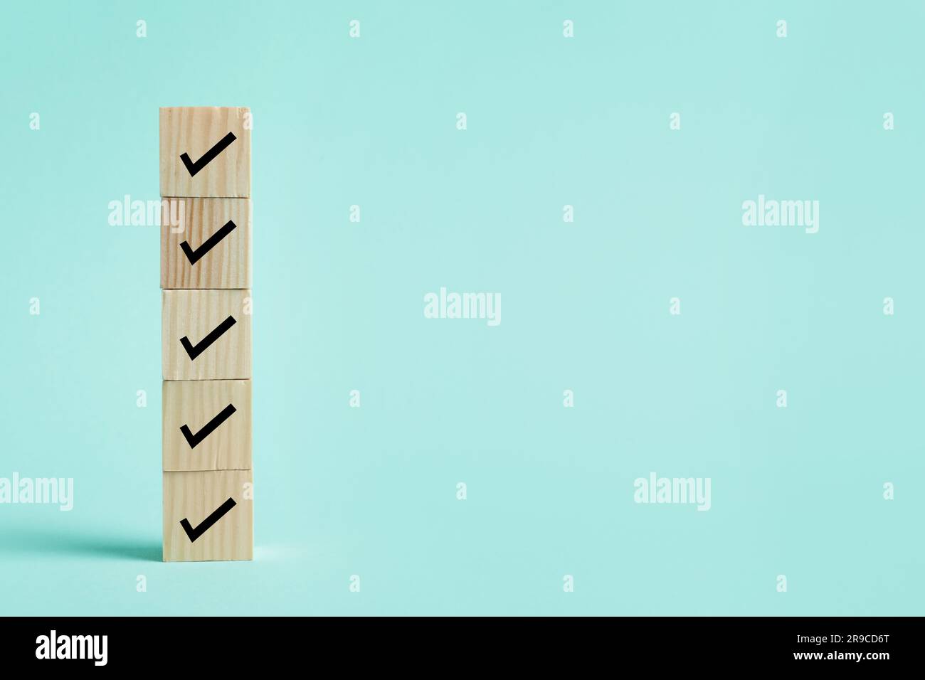 Stacked wooden cubes with check marks on turquoise background. Space ...