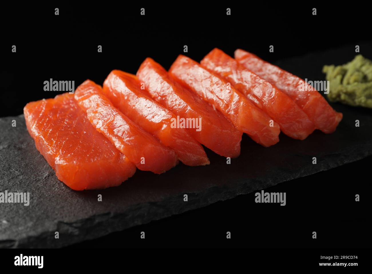 Delicious salmon sashimi and wasabi on black background, closeup Stock ...