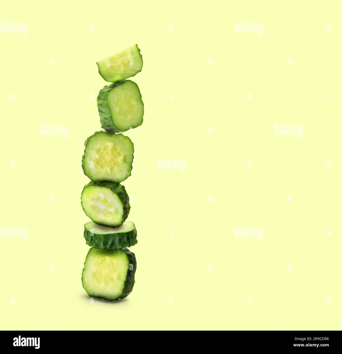 Stack of fresh cucumber pieces on pale light yellow green background ...