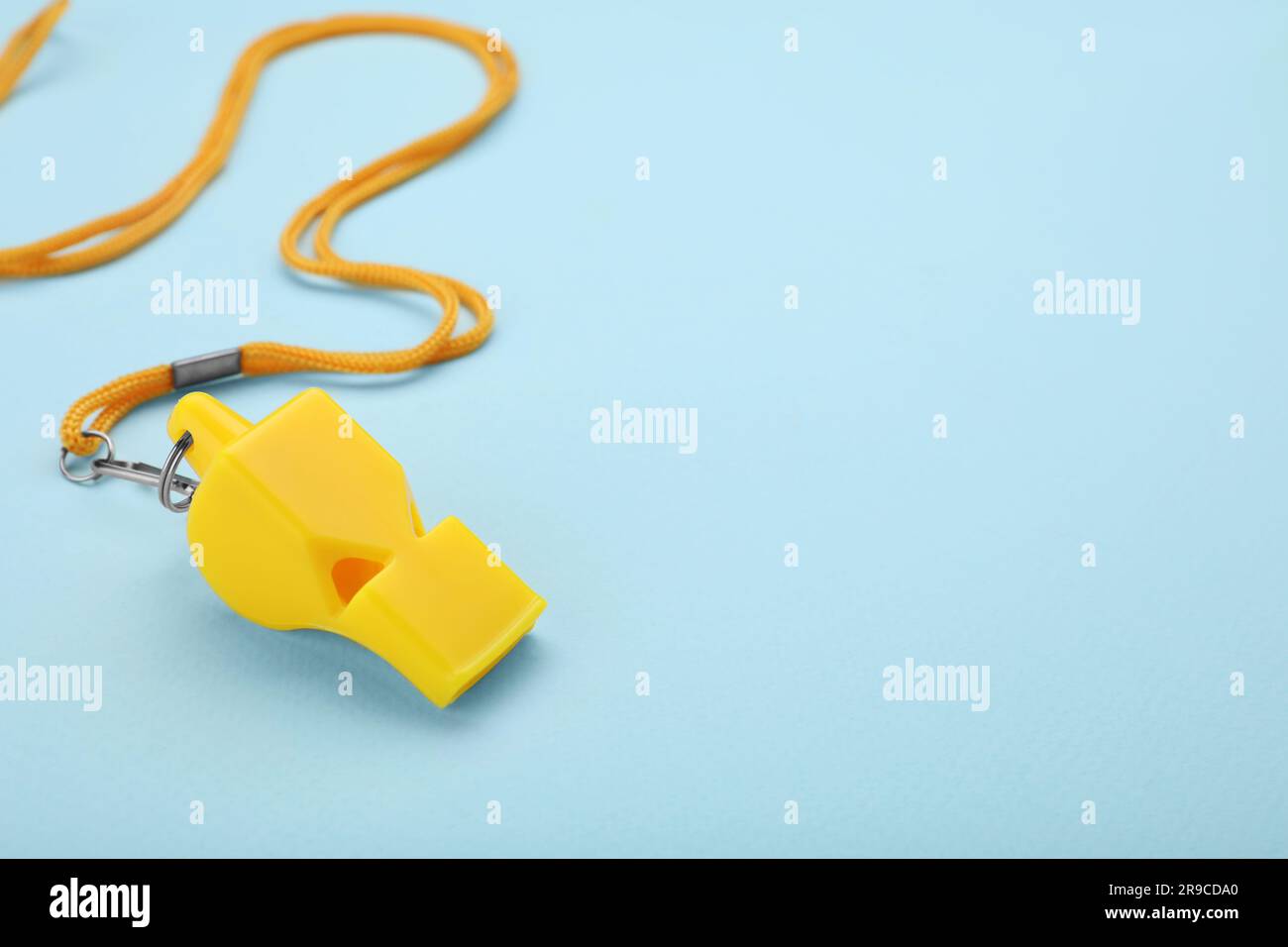 One yellow whistle with cord on light blue background. Space for text ...
