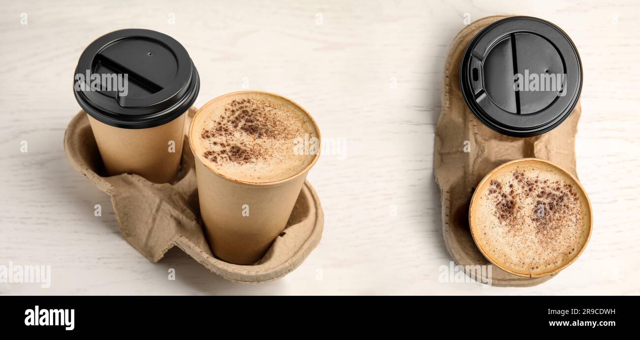 Takeaway paper cups with coffee in cardboard holder on white wooden ...