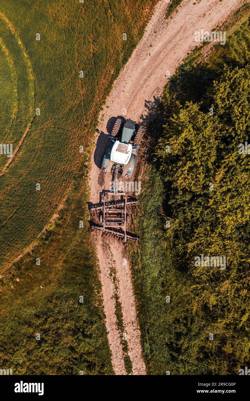 Aerial view of agricultural tractor with tiller attached on dirt road ...