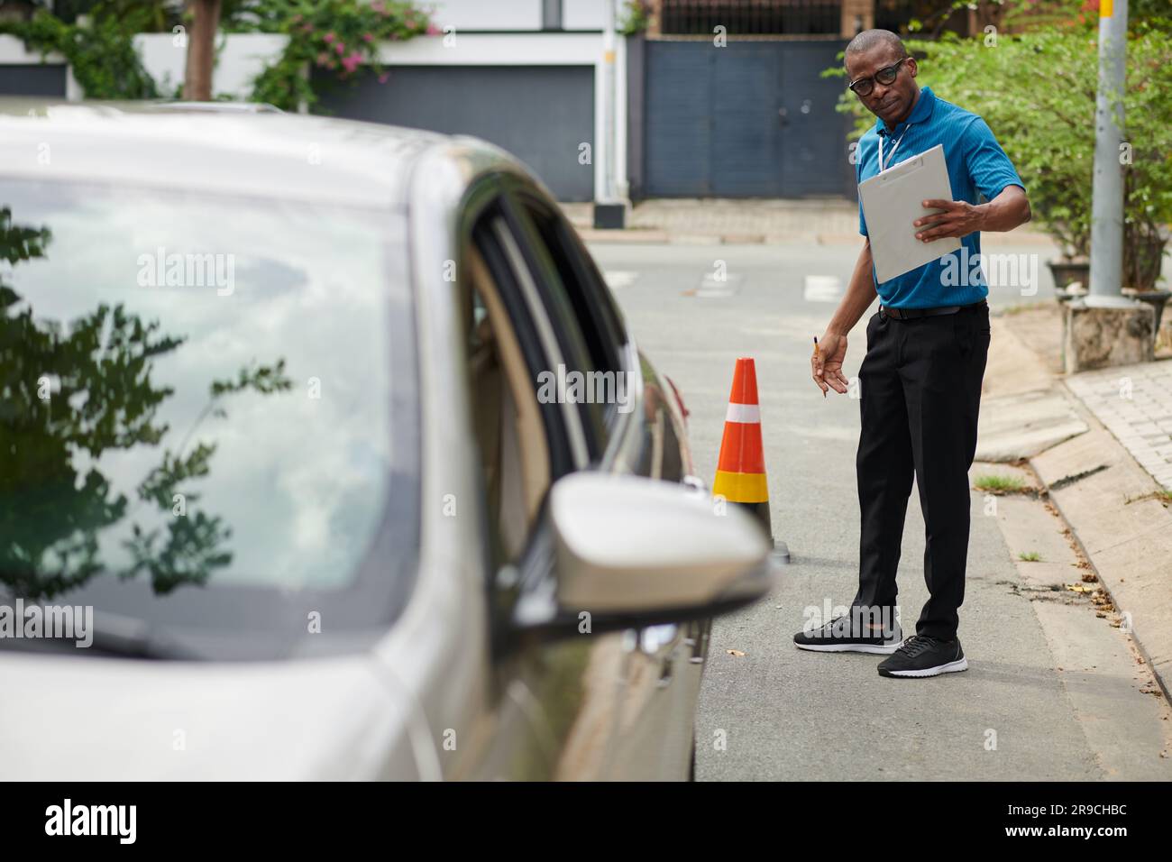 Driving school instructor controlling student parking between cones ...