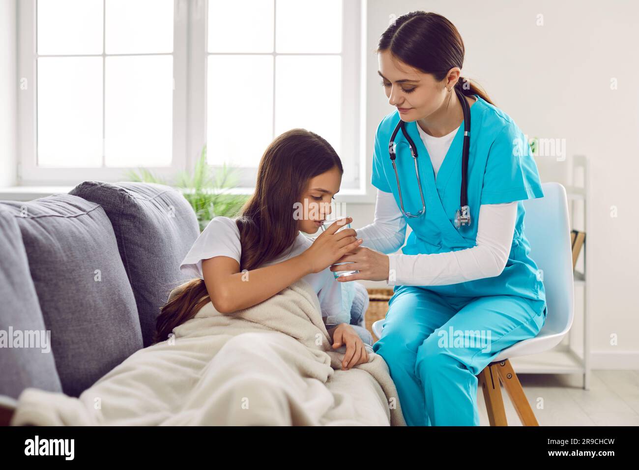 Woman doctor visits sick girl, helps her take medicine and gives her ...
