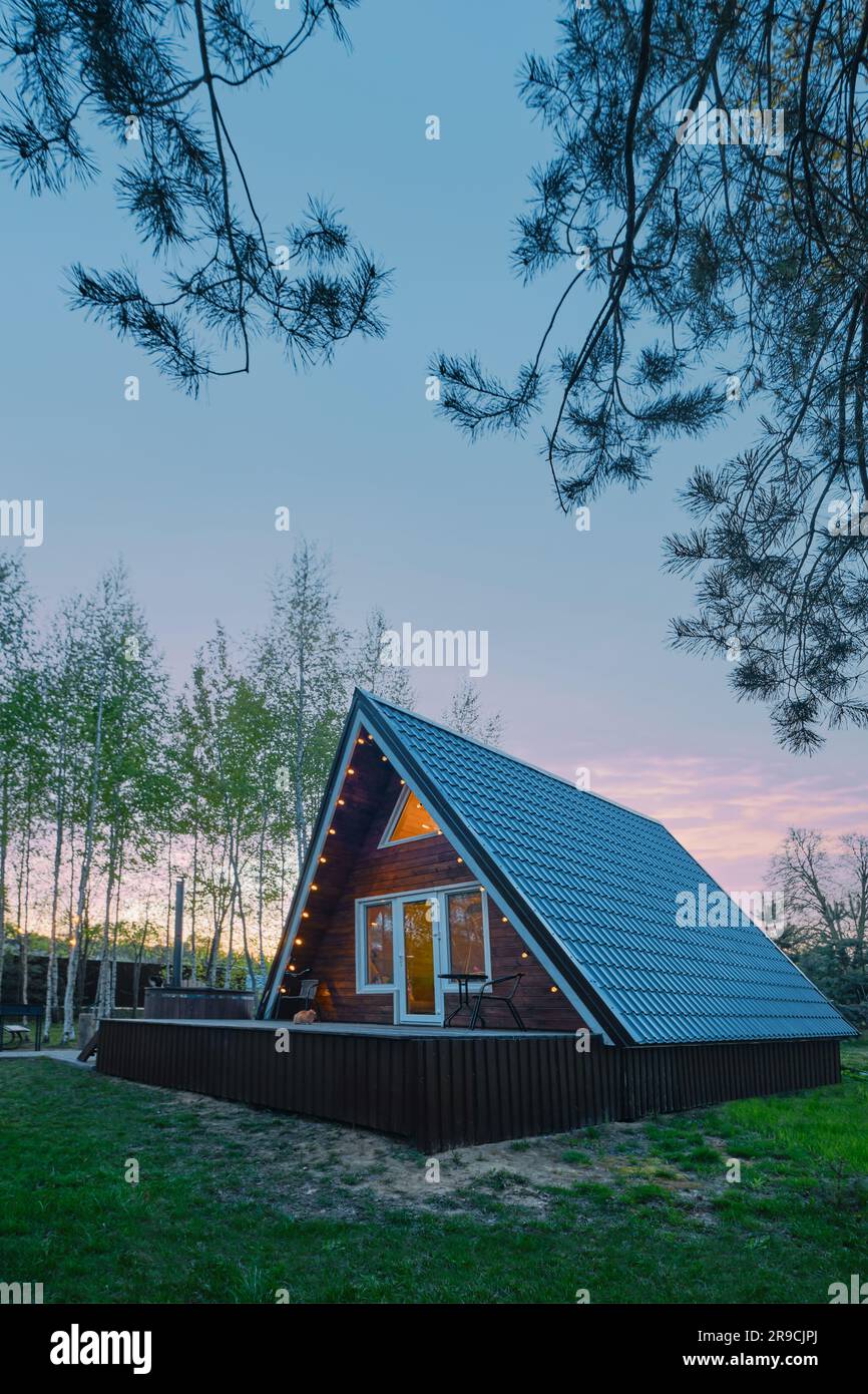 A-frame wooden cabin with light inside in early evening Stock Photo - Alamy