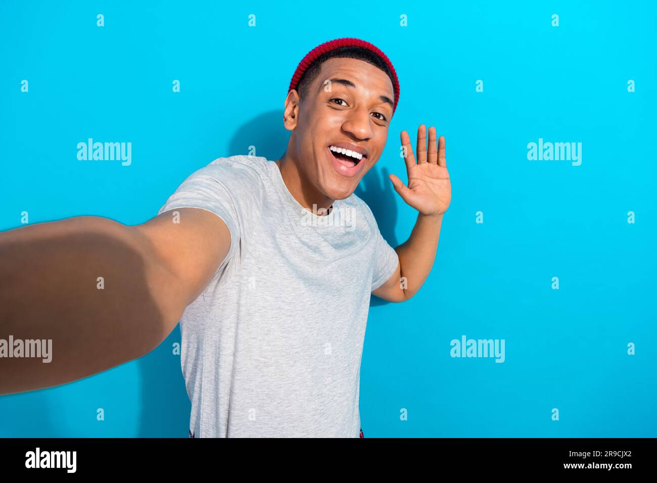 Photo of funky excited man wear grey t-shirt tacking selfie waving arm ...