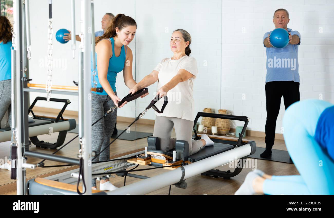 Pilates instructor assisting elderly woman hi-res stock photography and ...