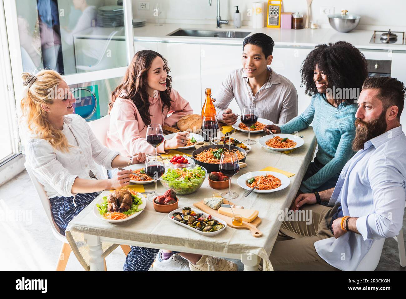 Group of multiethnic friends sitting at the table during lunch. Table ...