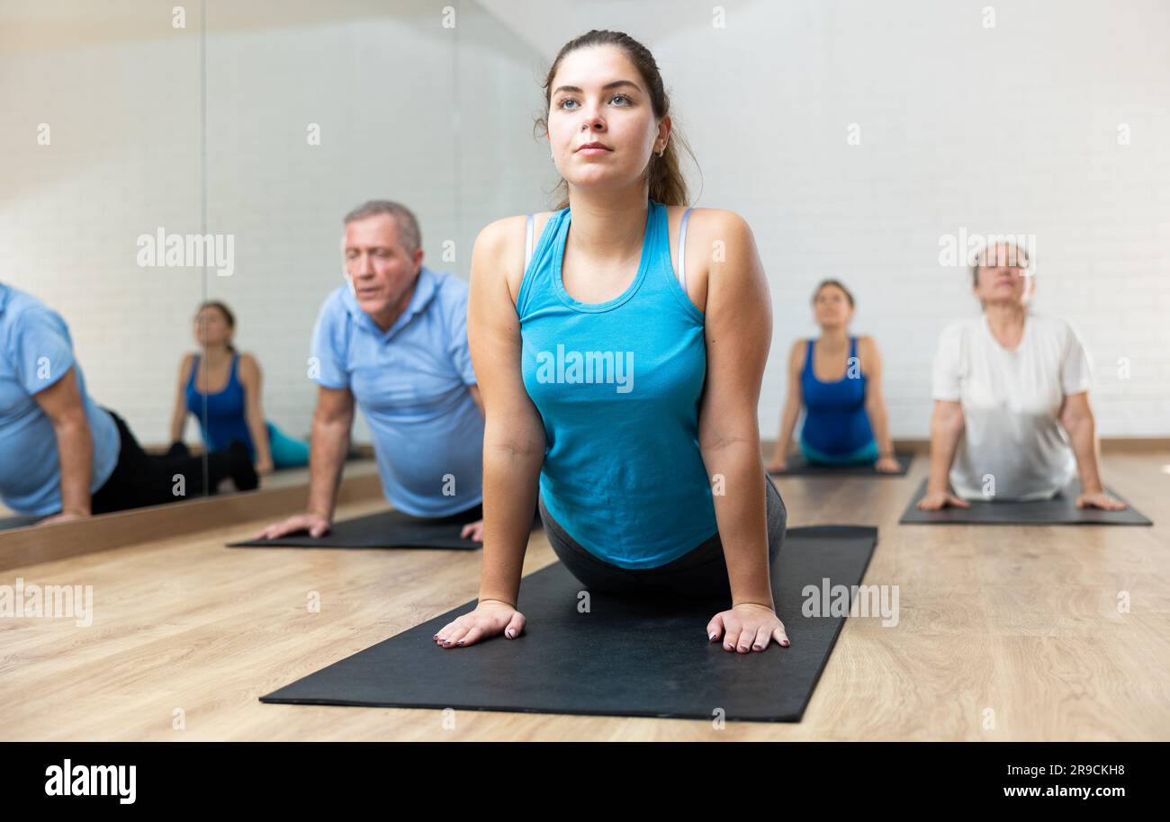 Class of male and women of different ages in active wear doing cobra ...