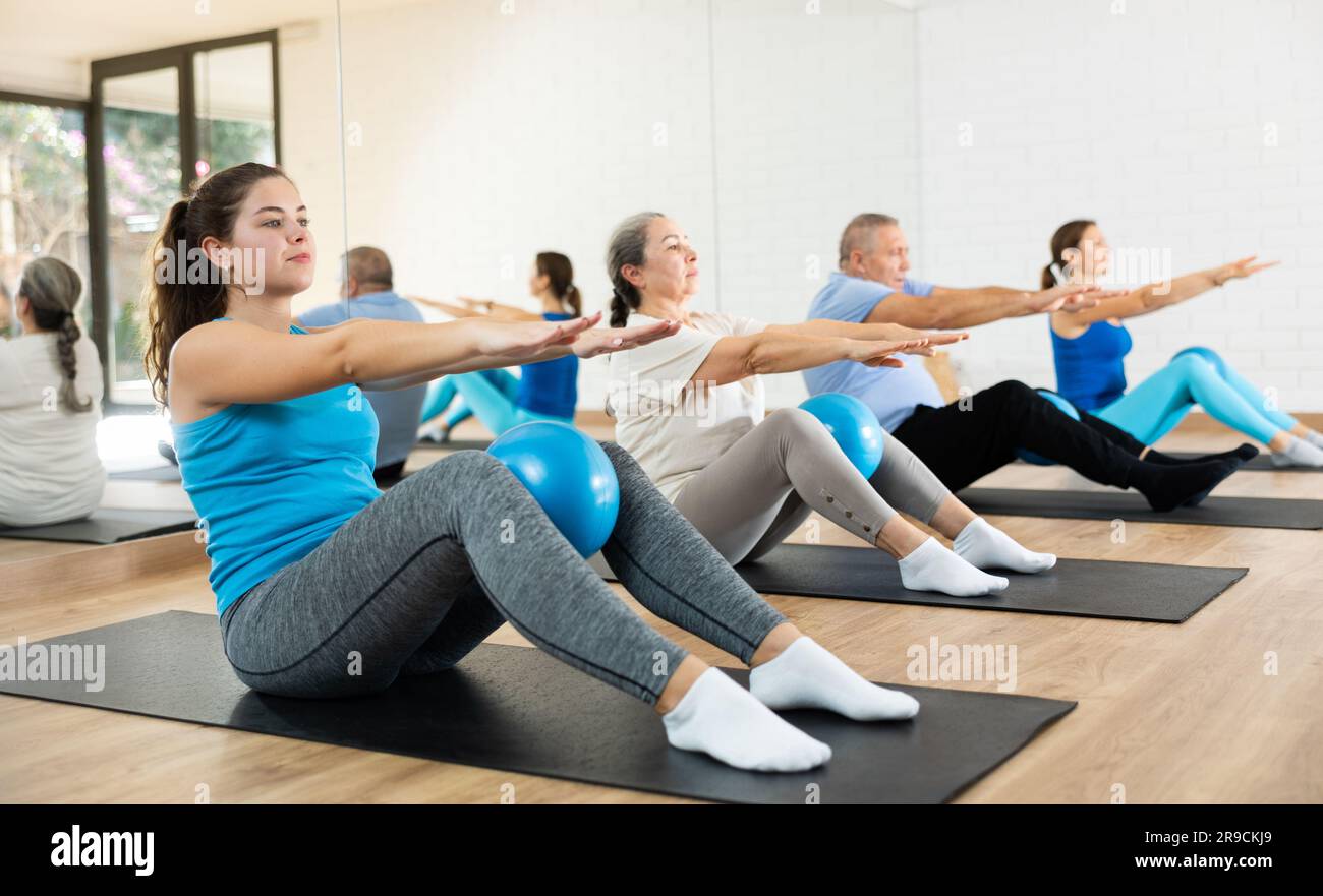 Sportive young woman doing pilates exercises with ball in gym area ...