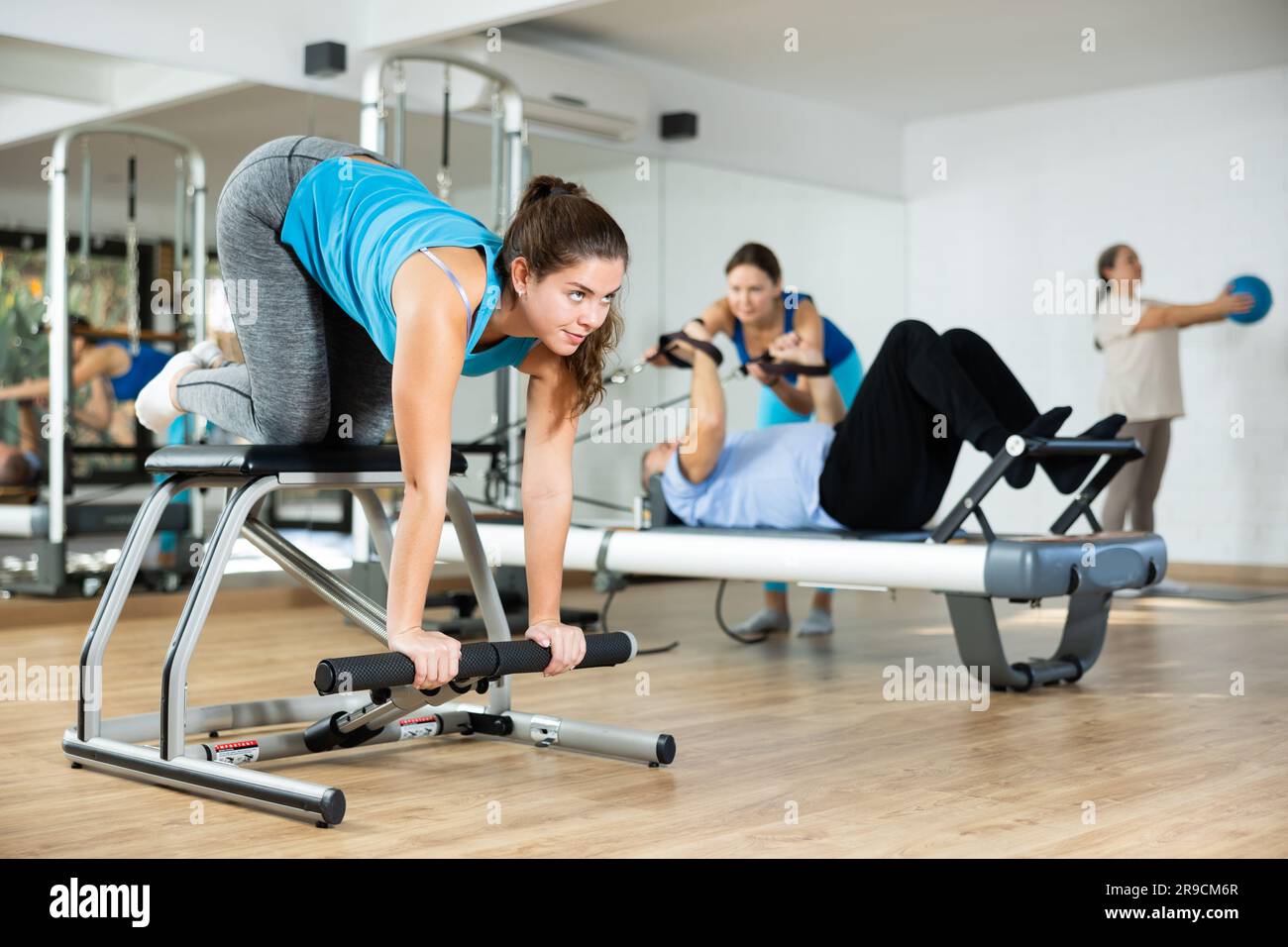 Sportive young woman doing pilates exercises on pedal pilates chair in ...