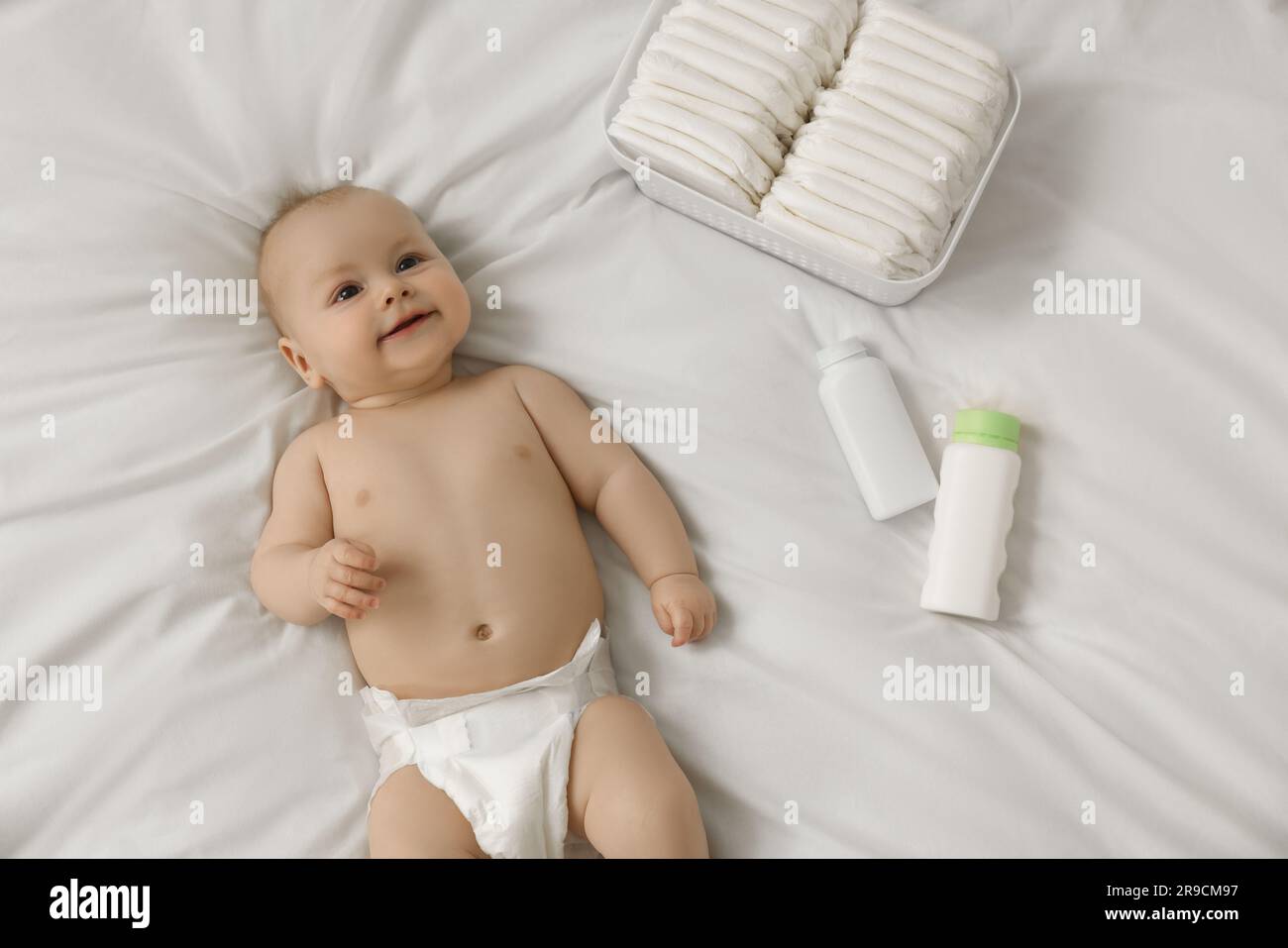 Cute baby, diapers and cosmetic products on white bed, top view Stock ...