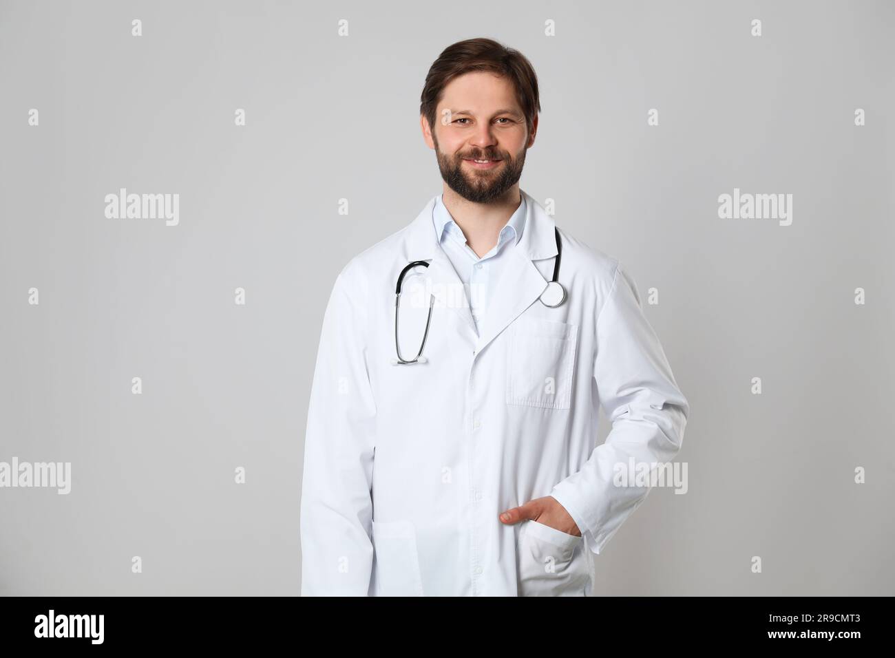 Doctor or medical assistant (male nurse) with stethoscope on light grey ...