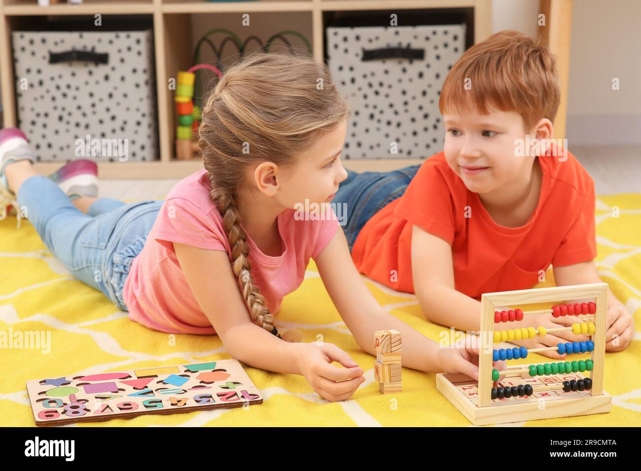 Happy children playing with math game kit on floor in room. Learning ...