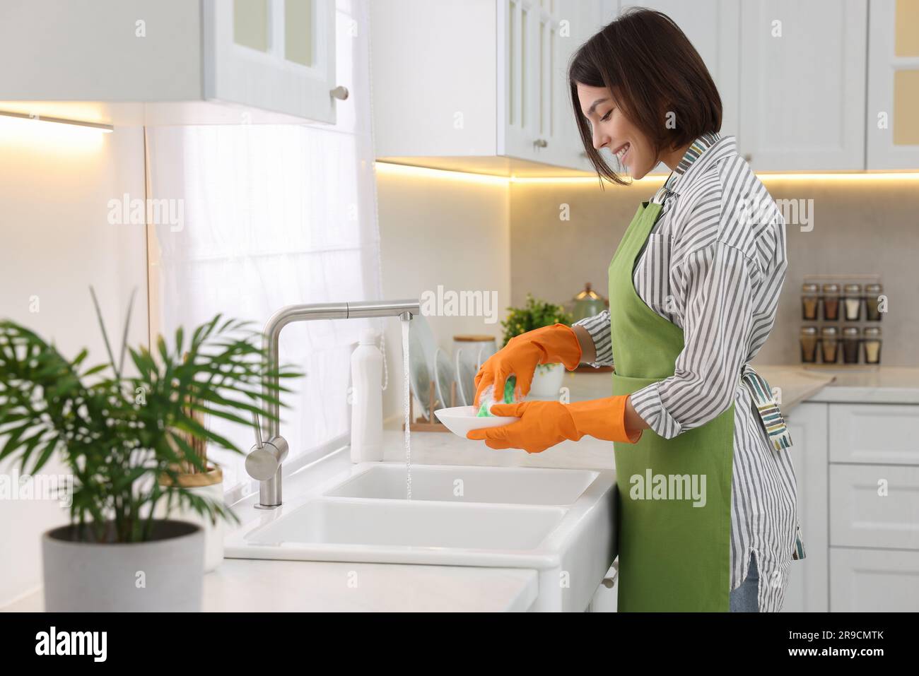 Happy young woman washing plate above sink in modern kitchen Stock ...