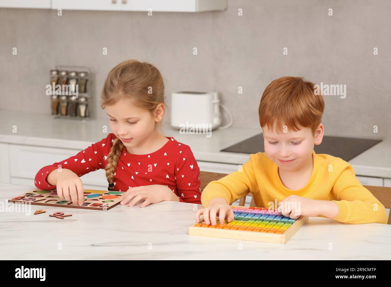 Children playing with different math game kits at white marble table in ...