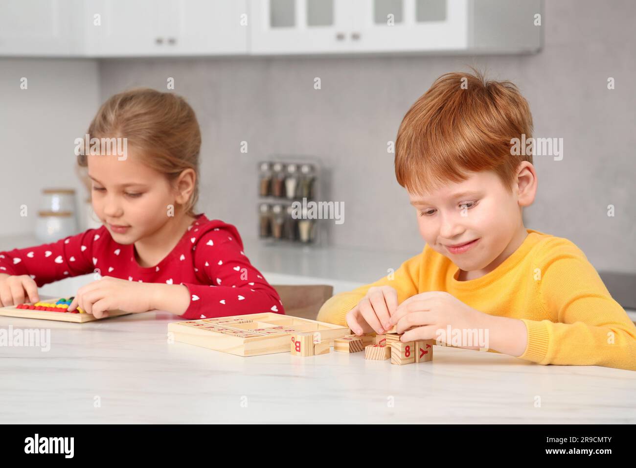 Happy children playing with different math game kits at white marble ...