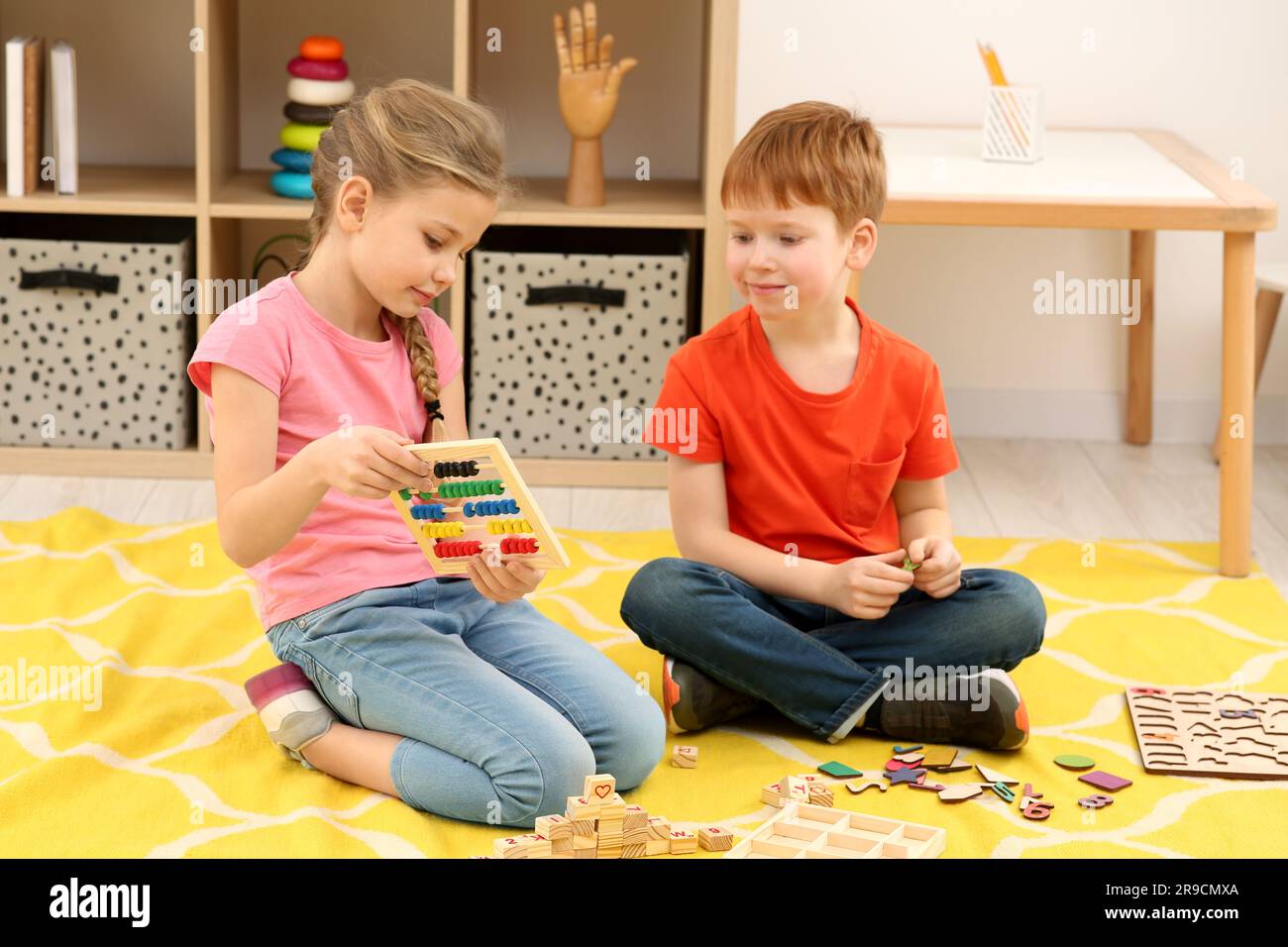 Children playing with different math game kits on floor in room. Study ...