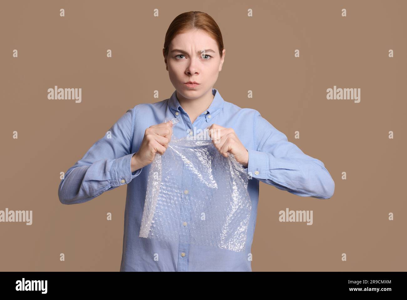 Angry Woman Popping Bubble Wrap On Beige Background Stress Relief