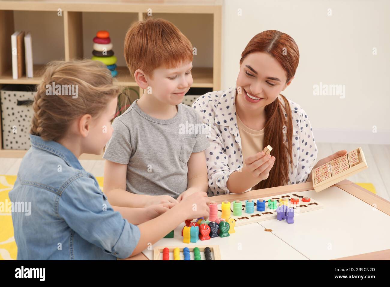 Happy mother and children playing with different math game kits at desk ...