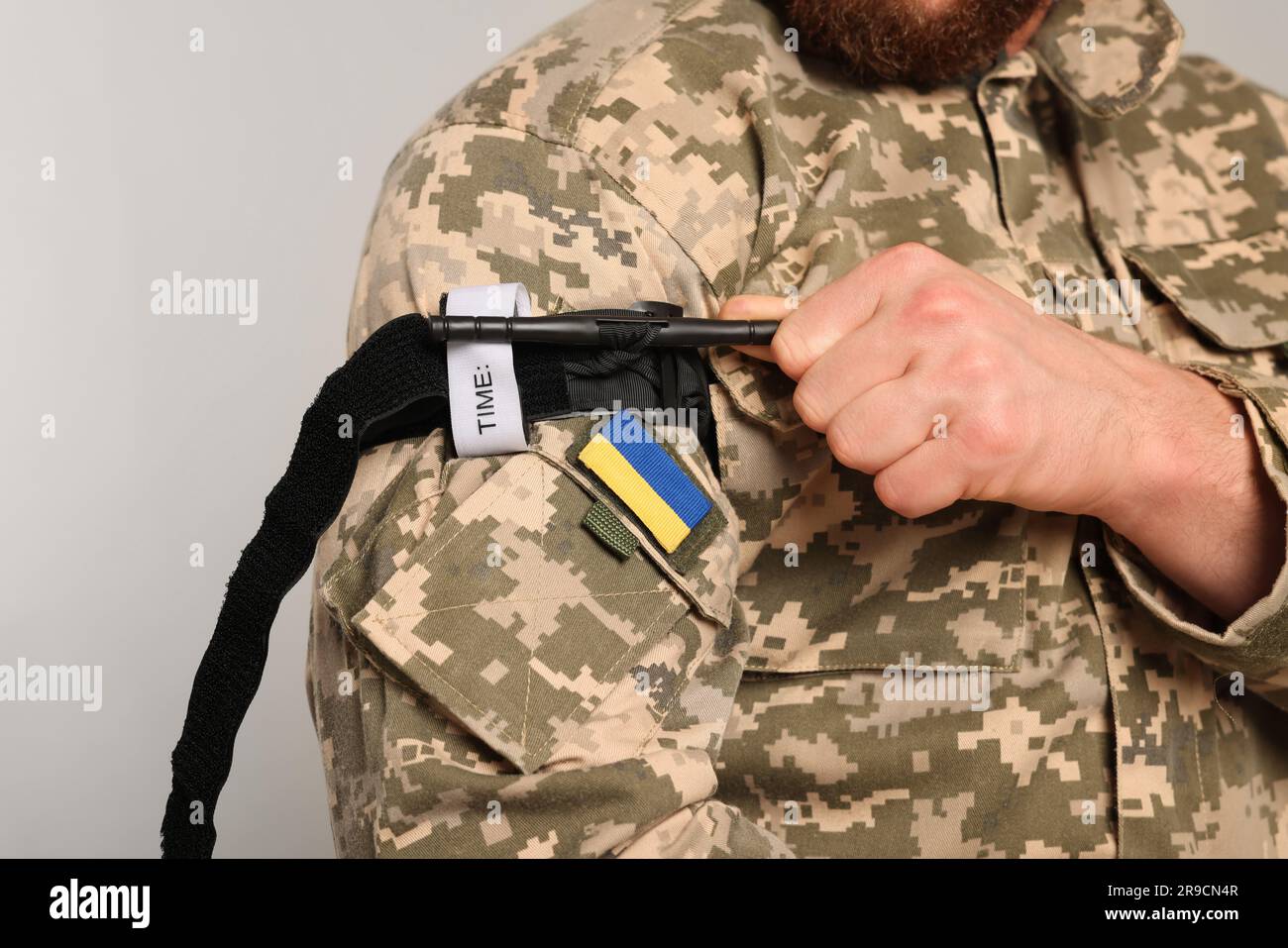 Ukrainian soldier in military uniform applying medical tourniquet on ...