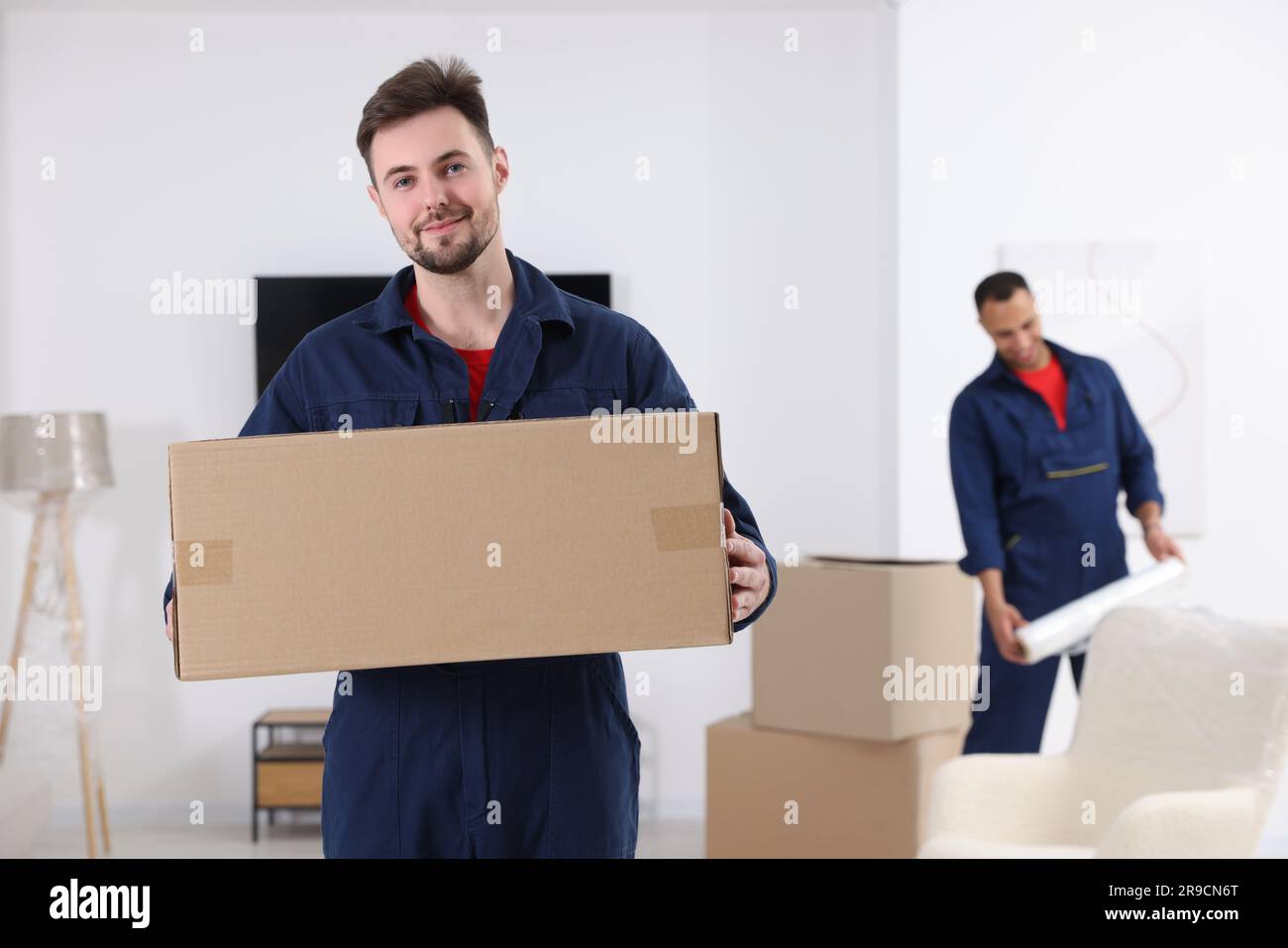 Male mover with cardboard box in house, space for text Stock Photo - Alamy