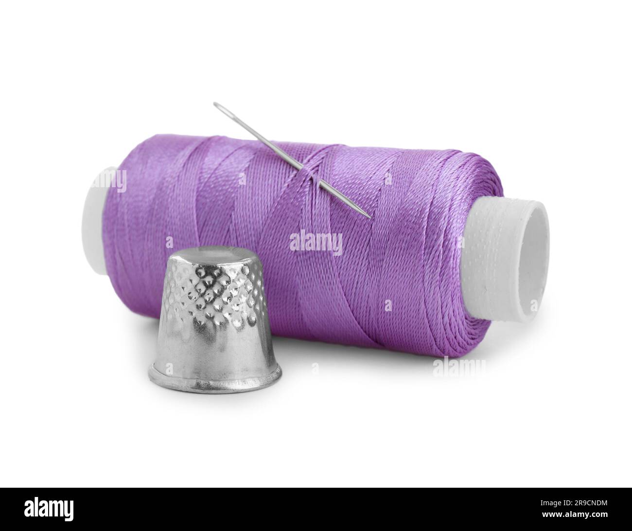 Thimble and spool of violet sewing thread with needle isolated on white Stock Photo - Alamy