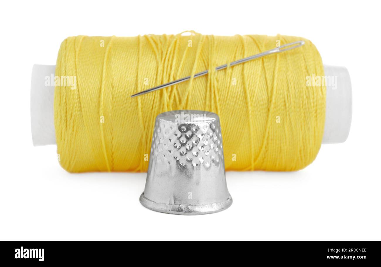 Thimble and spool of yellow sewing thread with needle isolated on white ...