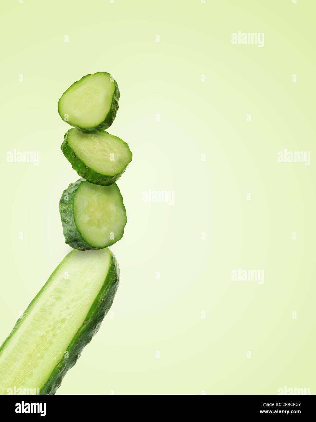 Cut fresh cucumbers on pale light green background, space for text ...