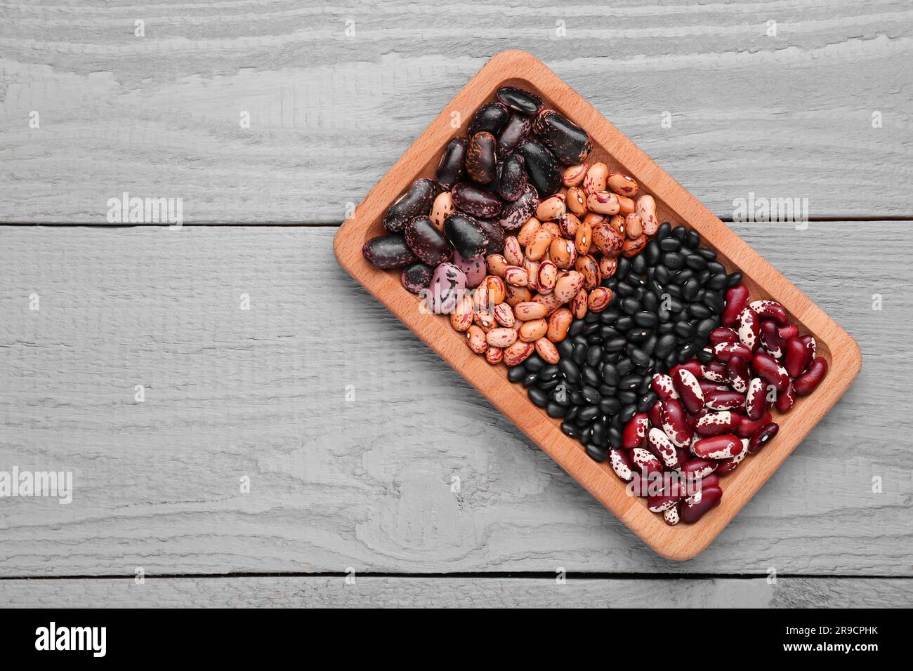 Plate with different kinds of dry kidney beans on light grey wooden ...