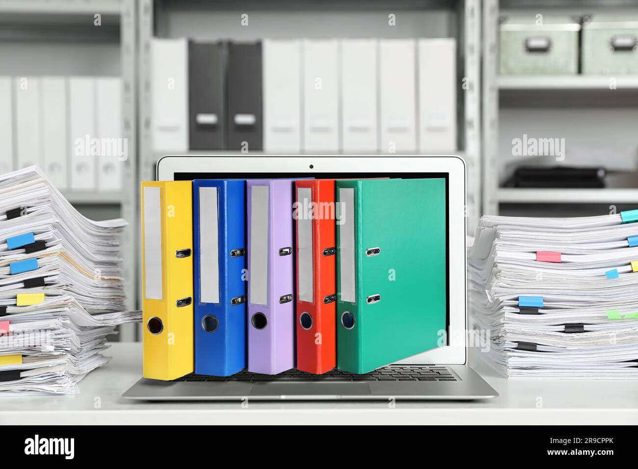 Digital archive. Laptop with folders sticking out of screen in office ...